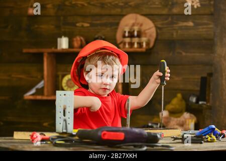 Kid boy holds screwdriver tool. Toddler on busy face plays with ...