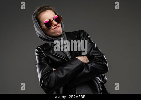A young girl with rough facial features in a black jacket shows ...