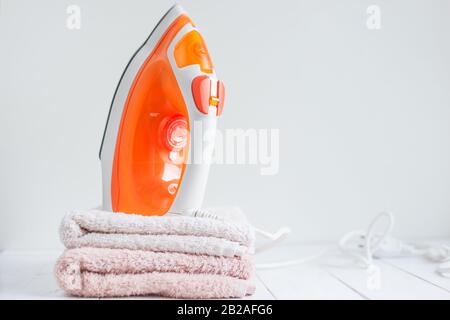 Stack of towels and electric iron on light blue background Stock Photo ...