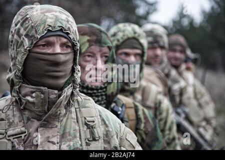 Group of skilled commandos wearing camouflage uniforms and masks ...