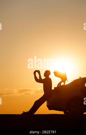Side view of silhouette of man relaxing in mountains and lighting fire ...