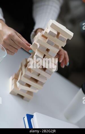 Playing Jenga. Man removing wooden block from tower on white background ...