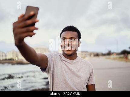 Selfie portrait Young cheerful fit woman in sports top with bag on her ...
