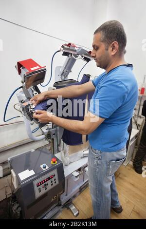 Man adjusting shirt on laundry dummy machine at launderette Stock Photo ...