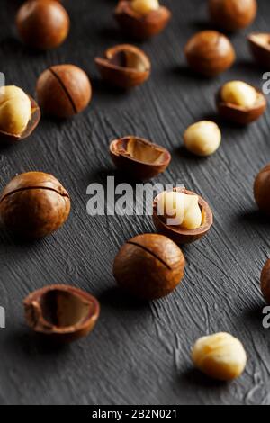 Purified and shell repeats macadamia nuts on black textural stone ...