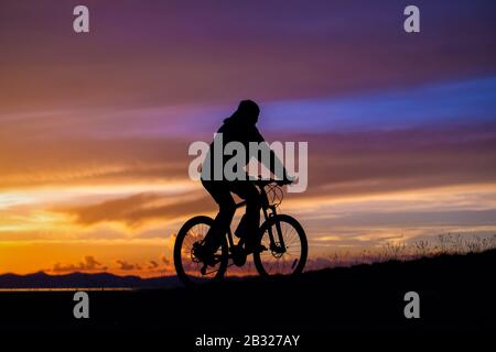 Silhouette of a bicyclist on the background of the sunset in the ...