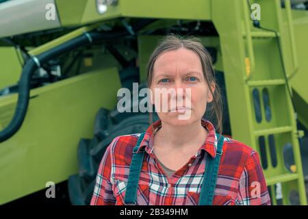 Female farmer posing in front of hay wagon. Portrait of woman farm ...