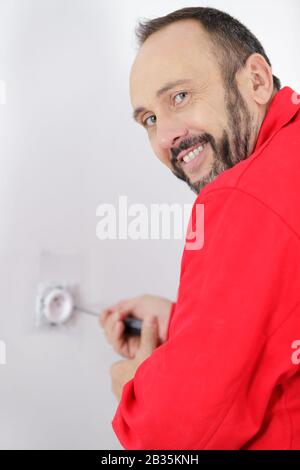 a happy electrician installs socket Stock Photo - Alamy