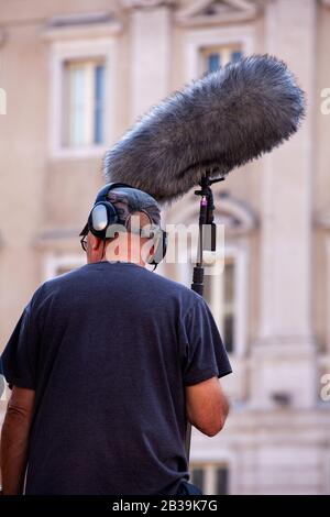 Behind the scene. Sound boom operator resting on the set and hold ...
