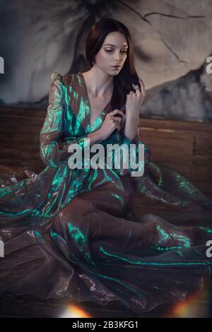 Young woman in blue peignoir drinking milk in disgust in home kitchen ...