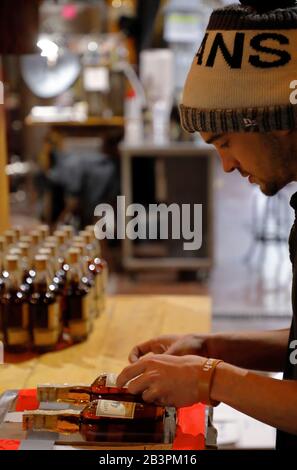 Hand labeling whiskey bottle inside Leiper's Fork Distillery.Franklin ...