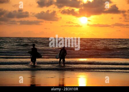 A panoramic image of two surfers walking in the sea at Fistral Beach on ...