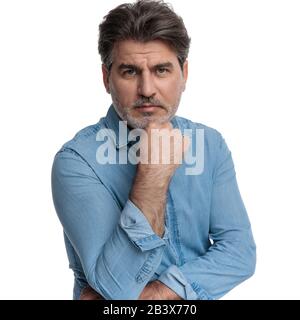Angry smart casual man frowning and pointing while sitting on a chair ...