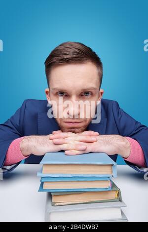 Emotional man holding stack of books on green background Stock Photo ...