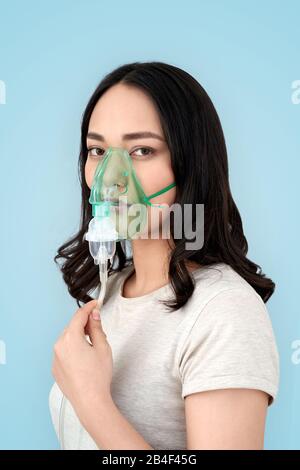 Young chinese woman wearing oxygen mask standing isolated on grey ...