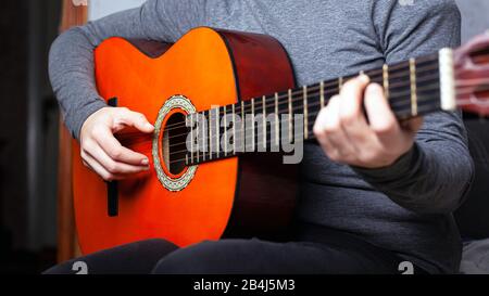 A girl playing acoustic guitar, close-up fingers on the strings. Black ...