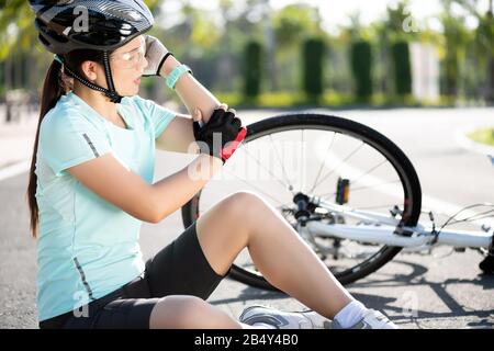 Female bicyclist with hurt leg sitting in park Stock Photo - Alamy