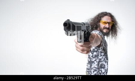 Portrait of the skinny, funny guy holding a gun Stock Photo - Alamy