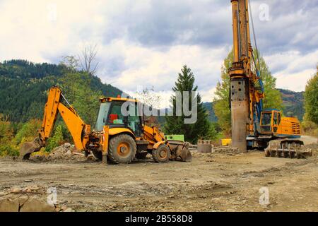 Machinery drilling and backhoe on construction site Stock Photo - Alamy
