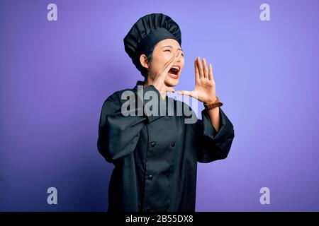 Excited angry asian chef wearing uniform standing isolated over white ...