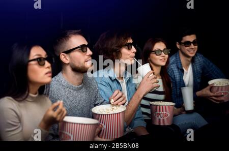 Premiere night. Young people with snacks watching 3D movie in cinema ...