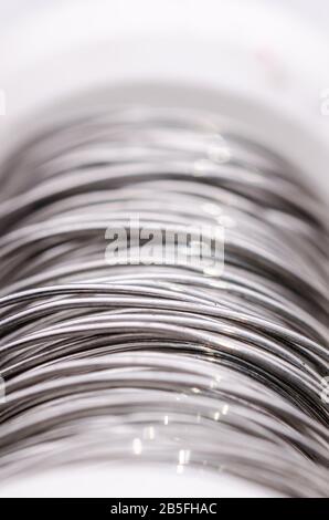 Metal wire on spindle, close up macro still life against white ...