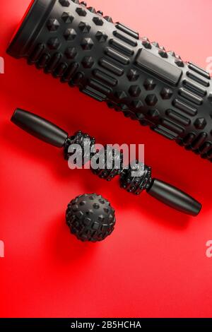 Black lumpy foam body massage roller on red background. For the ...