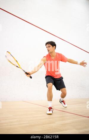 Squash player in action on a squash court (motion blurred image; color ...