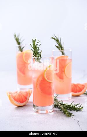 Citrus and rosemary fresh lemonade in glass on a white table at home ...