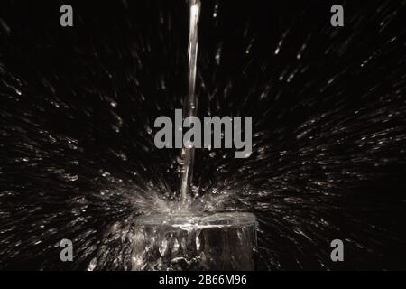 Water jet falling into a glass and generating a splash of water ...
