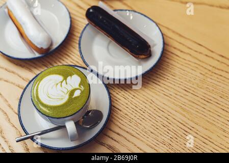 Green matcha with a eclair. Cozy coffee shop Stock Photo - Alamy