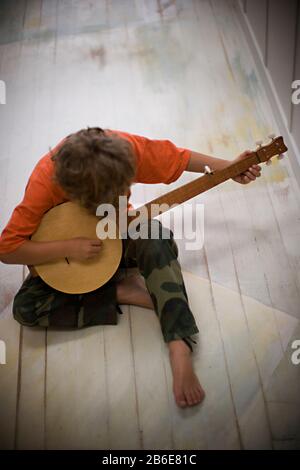 Young boy holding a banjo inside a bare room Stock Photo - Alamy