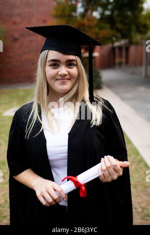 Happy caucasian graduated girl with long brown hair showing her diploma ...