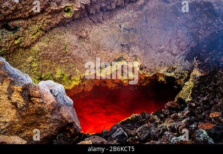 Looking into an active basalt lava flow from the solidified carapace, with red, incandescent ...