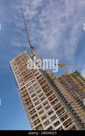 construction crane being built using a secondary crane shot against ...