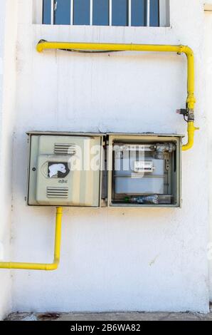 Yellow Gas Meter Box with gas pipes in it on a wall outside the house ...