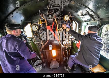 Footplate crew adjust dials and steam regulators aboard the Great ...