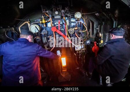 Footplate crew adjust dials and steam regulators aboard the Great ...