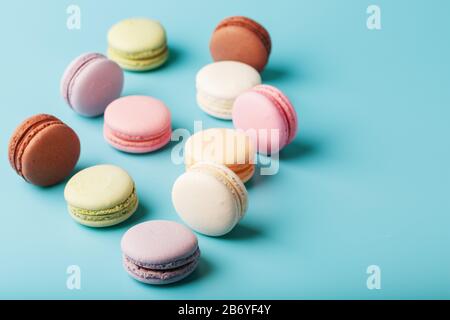 Macaroni cookies of different colors are scattered on a blue background ...