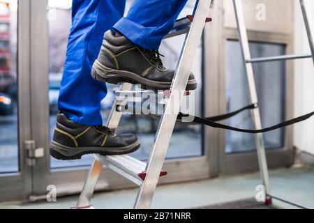Low Section View Of A Handyman's Foot Climbing Ladder Stock Photo - Alamy