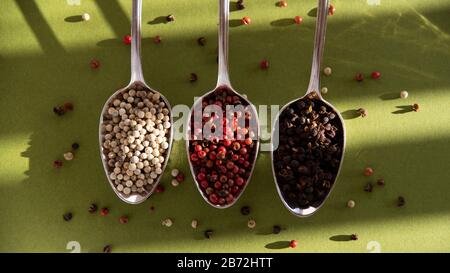 Different peppers and pink berries in spoons Stock Photo - Alamy