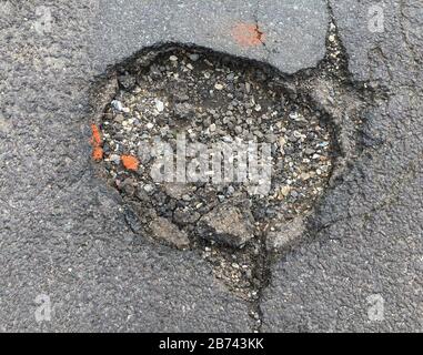 A large pothole forms in a road surface in Godalming, Surrey, England ...