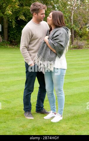 Young couple expecting a baby standing over pink background thinking ...