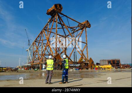 Construction workers in front of an offshore oil and gas platform also ...
