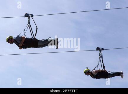 Two men use a zipline to fly over a 1, 000 metre stretch of the ...