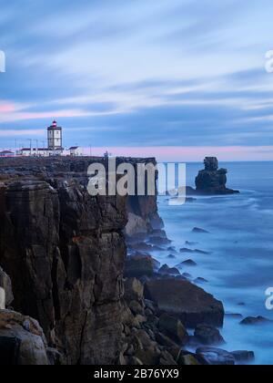 Lighthouse over the cliff on cloudy sunset Stock Photo - Alamy