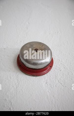 Closeup of an old rusty school bell on a white wall under the lights ...