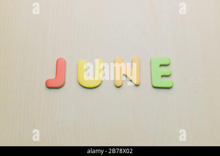 June word written with colorful letters on wooden background, top view ...
