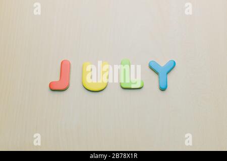 July word written with colorful letters on white marble stone ...