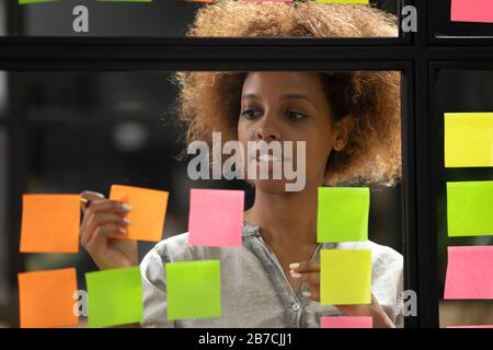 African american employee working on laptop, looking at camera, smiling ...